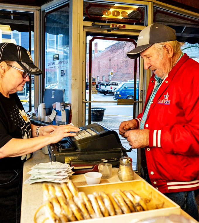 The daily ritual: a regular customer settling his bill while eyeing those fresh-baked cookies. Some traditions are too delicious to break.