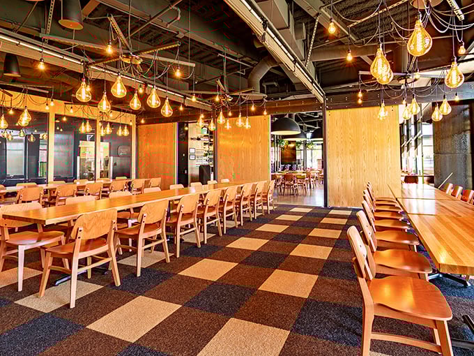 Edison bulbs dangle like modern jellyfish above communal tables, creating the perfect setting for breaking bread and cracking shells.