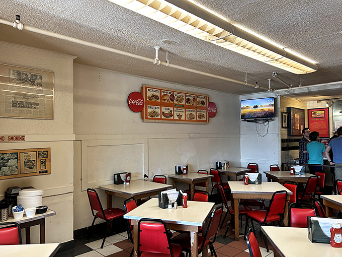 Red chairs against white tables create a democratic dining room where CEOs and construction workers sit elbow to elbow, united by barbecue.