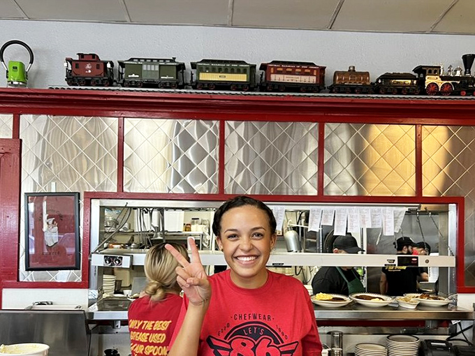 That smile says, "Yes, our grits really are that good." The peace sign is just bonus hospitality&mdash;Southern charm in visual form.