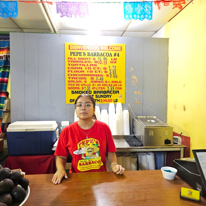 Friendly staff member wearing the restaurant's signature shirt, ready to serve up San Antonio's finest barbacoa experience.