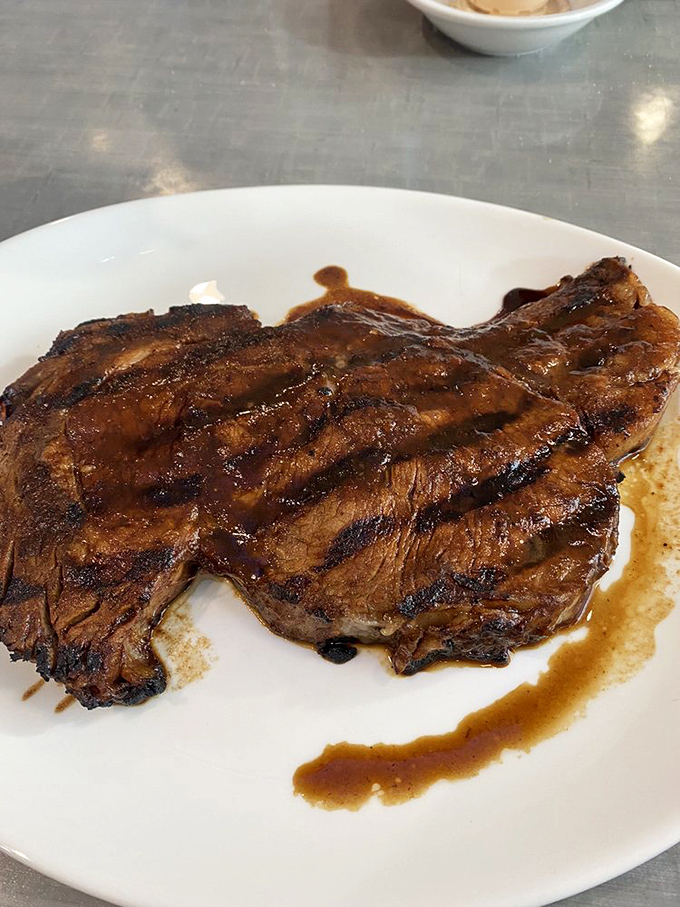 This steak arrives looking like it graduated summa cum laude from the school of perfectly grilled perfection.
