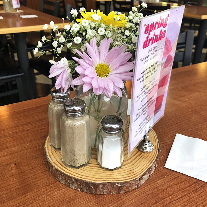 Fresh flowers and salt shakers on a wooden slice—small touches that say "we care." That spring drinks menu isn't just seasonal—it's an invitation.