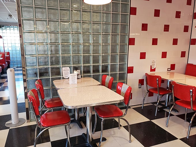 Glass block dividers and speckled tabletops create intimate dining spaces that feel both retro and timeless.