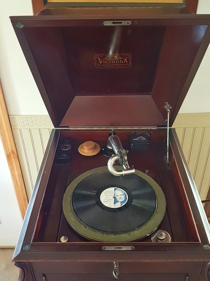 The Victrola record player stands ready to spin tales from another era. Before Spotify playlists, this mahogany beauty was the soundtrack to someone's love story.