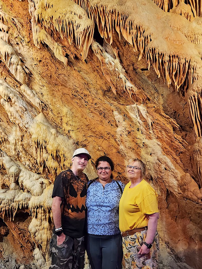 Fellow explorers pose against a backdrop of flowing stone draperies, providing scale to these massive formations that dwarf human visitors.