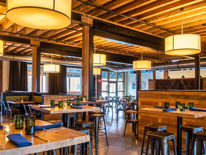 Wooden beams, drum lights, and thoughtful spacing create an atmosphere both spacious and intimate. Every table feels like the best seat in the house.