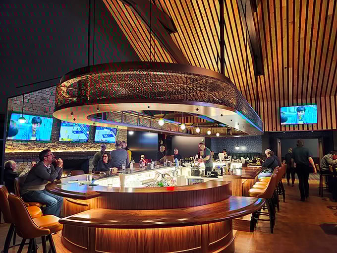 The curved bar invites conversation while the dramatic lighting fixture above serves as both art installation and beacon for thirsty patrons.