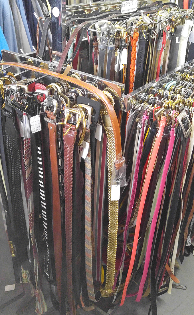 A leather rainbow of belts dangles in orderly rows, each one having faithfully held up someone else's pants before potentially holding up yours.