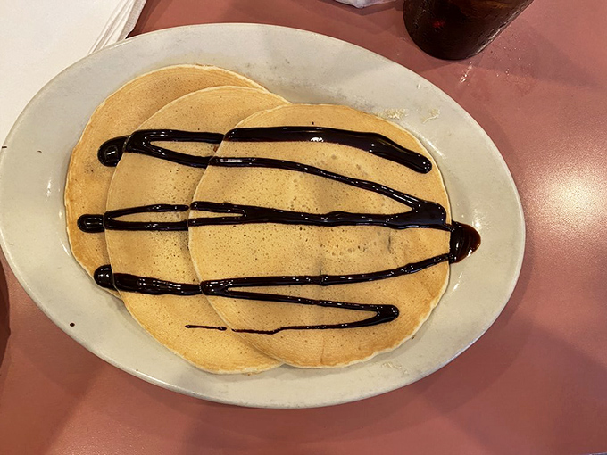 Pancakes dressed in their Sunday best &ndash; chocolate drizzle creating the kind of breakfast masterpiece that makes you pause before diving in.