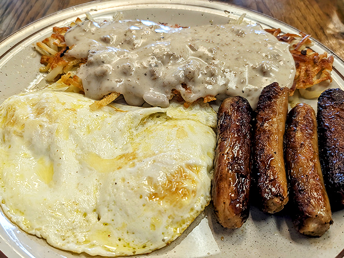 The breakfast trinity: perfectly cooked eggs, hash browns smothered in country gravy, and sausage links with that satisfying snap.