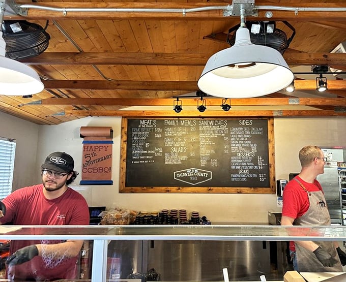 Where the magic begins: the counter where meat maestros orchestrate your barbecue symphony beneath wooden beams and pendant lights.