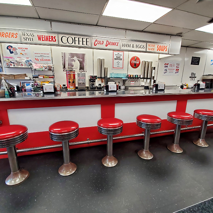 A row of empty counter stools waiting for hungry patrons—red vinyl thrones for everyday royalty seeking comfort food coronations.
