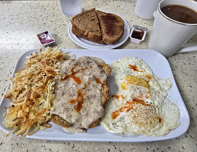 Country fried steak with eggs that doesn't just break your diet—it shatters it into delicious pieces. That pepper sauce zigzag isn't just garnish—it's artwork.