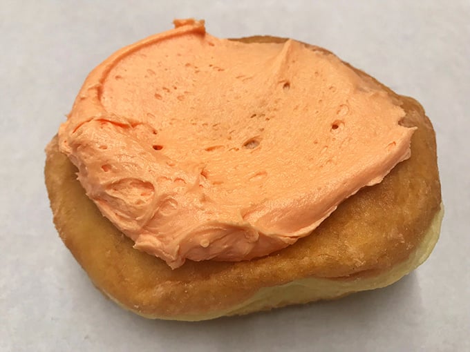 The creamsicle donut brings childhood summer memories to breakfast—orange icing atop golden dough that tastes like nostalgia itself.