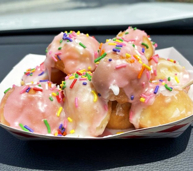 Donut holes in pink glaze with sprinkles&mdash;bite-sized joy bombs that somehow taste better than their full-sized counterparts, defying all laws of physics.