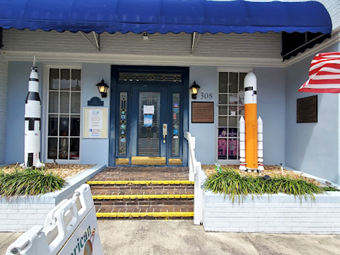 The blue awning and rocket sentries signal you've arrived somewhere special. This unassuming entrance holds treasures that would make any space enthusiast weak-kneed.