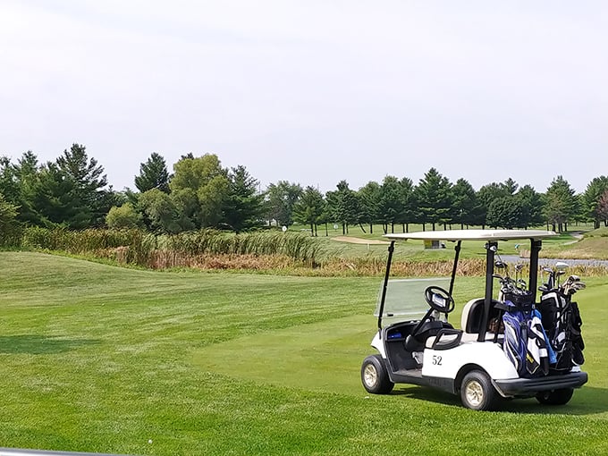 A solitary golf cart waits on manicured greens, promising a peaceful round where water hazards might include Great Lakes views.
