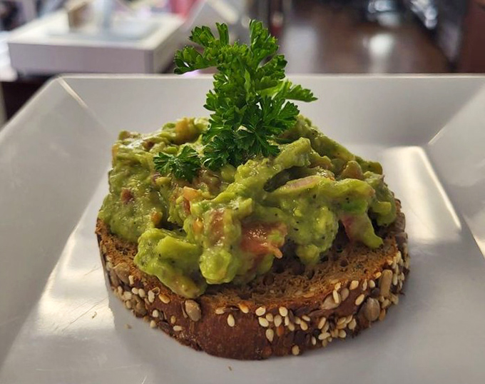 This isn't just avocado toast; it's a verdant mountain of perfectly seasoned guacamole atop hearty bread that makes "eating your greens" a pleasure, not a chore.