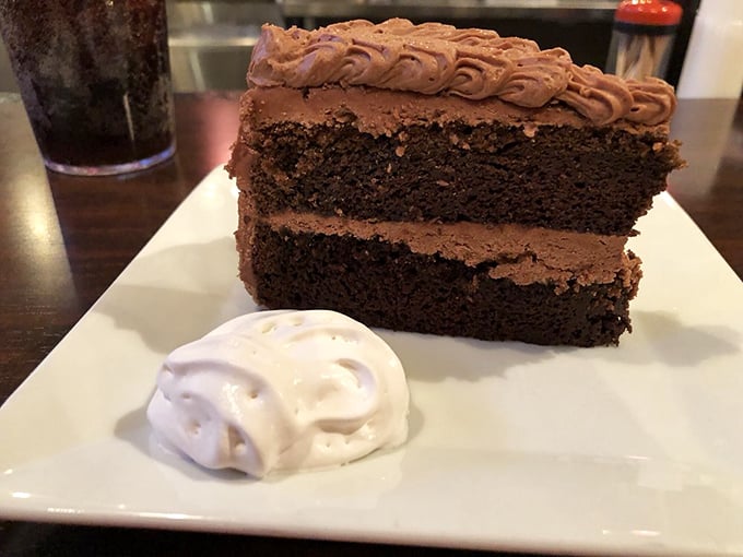 A slice of chocolate cake that doesn't just end the meal—it crowns it. Two layers of decadence with frosting that's been applied with both generosity and skill.