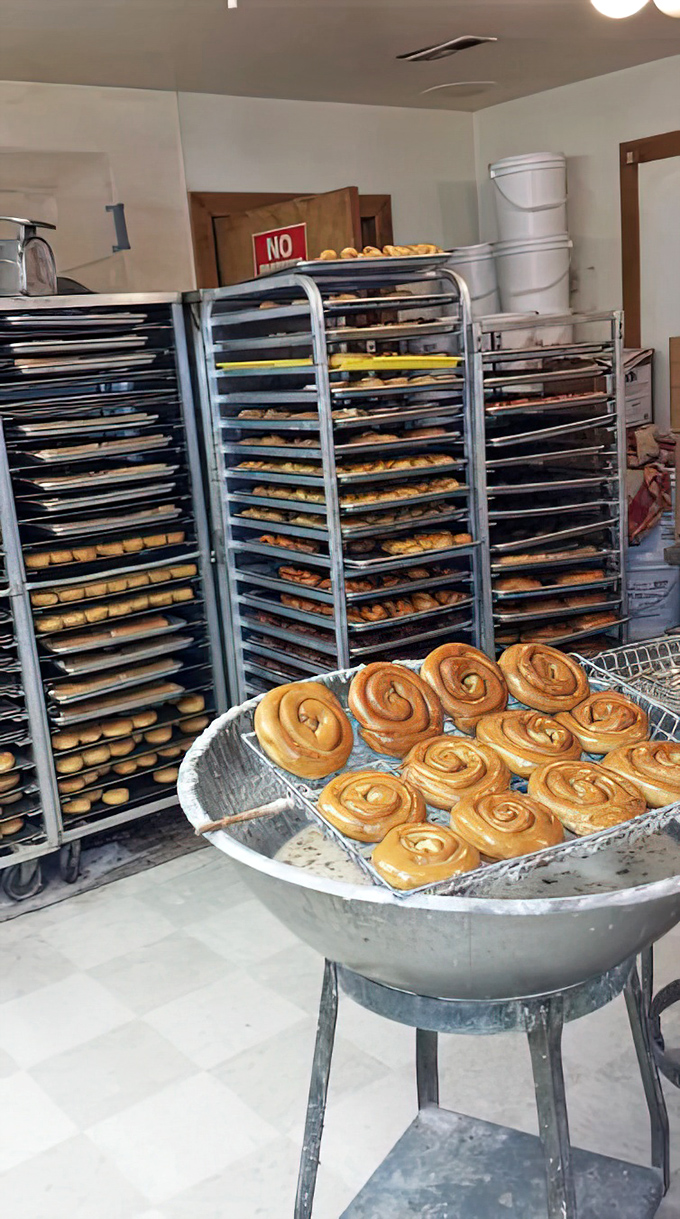 Cinnamon rolls waiting for their moment of glory. Behind them, racks of future happiness cool patiently before meeting their adoring public.