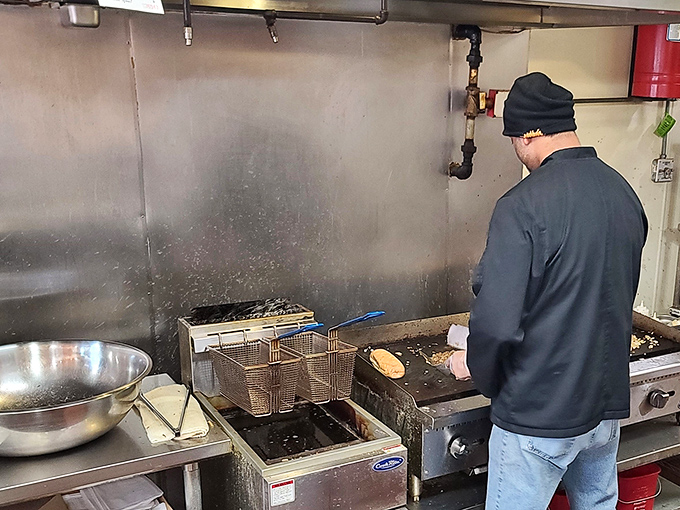 A chef in his element, working the flat-top with practiced precision. This is where cheesesteak dreams come true, one sandwich at a time.