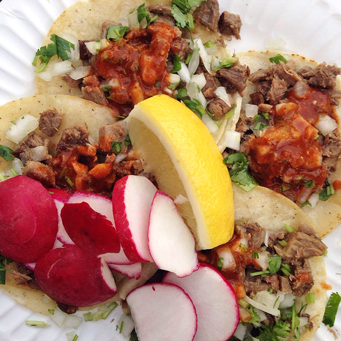 Lengua tacos garnished with radish medallions and a lemon crown &ndash; a dish that transforms the hesitant into true believers with just one bite.