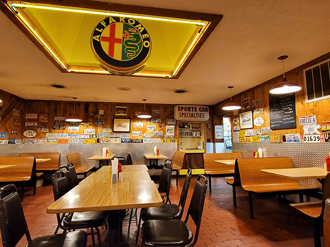 Under the watchful eye of an Alfa Romeo sign, diners enjoy meals in a space where automotive passion meets culinary comfort.