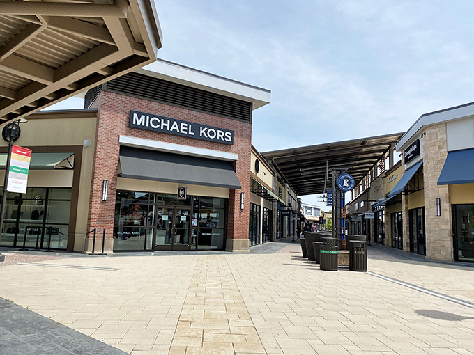 Michael Kors: the gateway drug to luxury shopping, where gold-tone hardware gleams under perfect lighting to maximize impulse purchases.