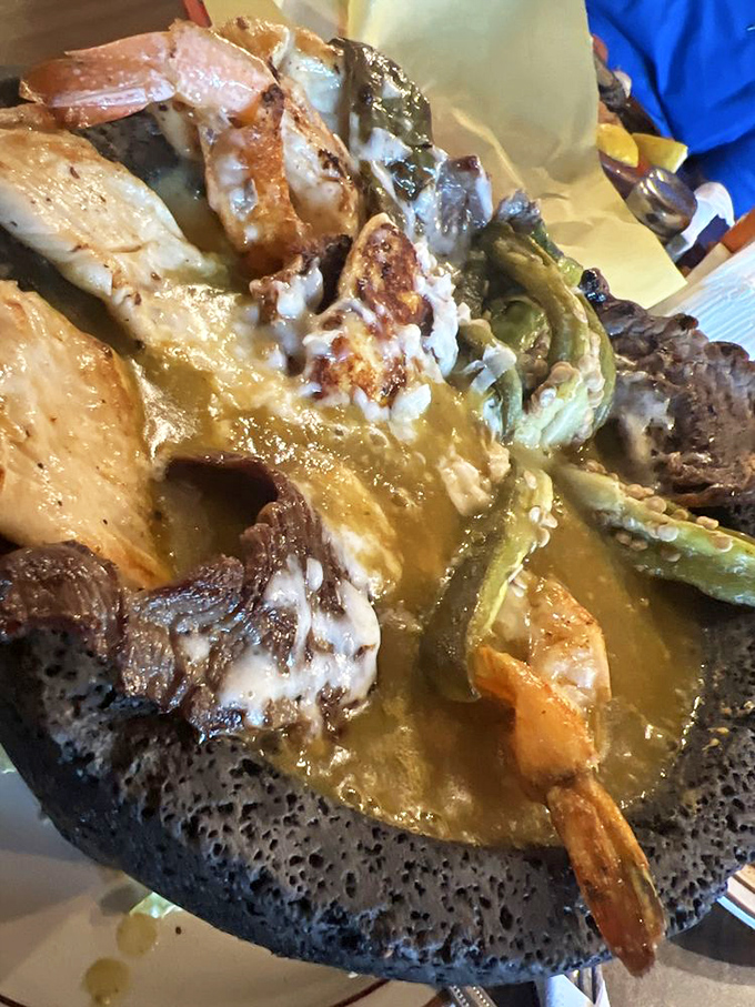 The molcajete arrives like a volcanic eruption of flavor &ndash; meat, shrimp, and vegetables swimming in savory sauce within a traditional stone bowl.