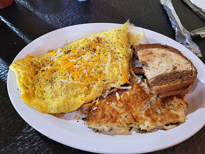 Breakfast done right: a cheese-laden omelet with hash browns that achieve that perfect crisp-outside, tender-inside balance. Morning glory on a plate.