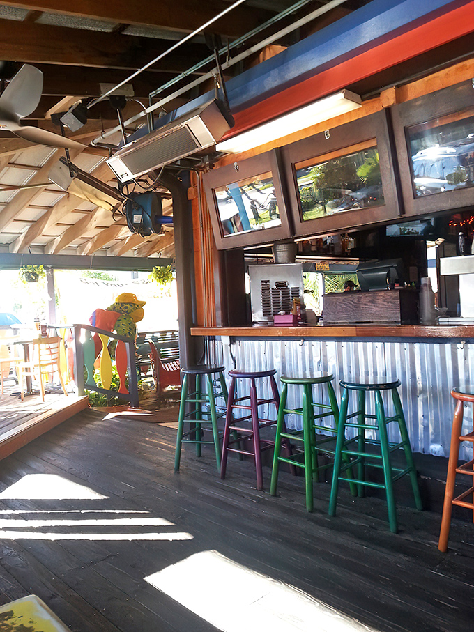 Stools in rainbow colors invite you to perch and ponder. Sunlight streams through this outdoor bar area, nature's spotlight on your next cold beverage.
