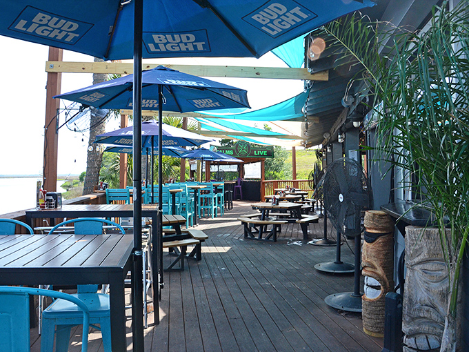 Blue umbrellas create islands of shade on the sun-drenched deck, where every table offers a side of vitamin D with your seafood feast.