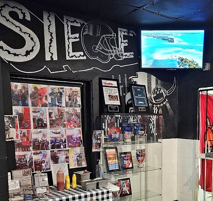 The wall of fame showcases local sports pride and customer memories&mdash;a community scrapbook seasoned with ketchup and nostalgia.