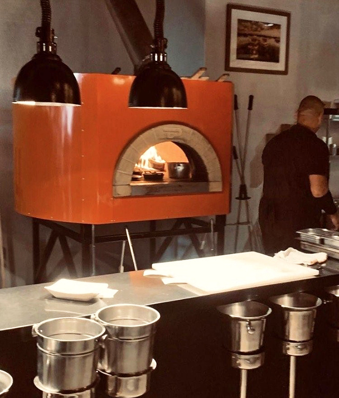That vibrant orange wood-fired oven isn't just for show—it's where magic happens at 700 degrees. Pizza's fancy cousin has arrived at the seafood party.