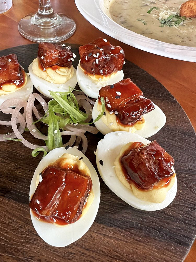 Deviled eggs wearing pork belly hats? This is what happens when comfort food gets dressed for the red carpet. Pure genius on a slate board.