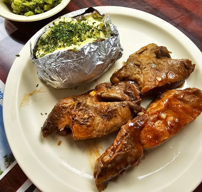 Ribs glistening with sauce alongside a foil-wrapped potato—proof that diners can do dinner with impressive authority.