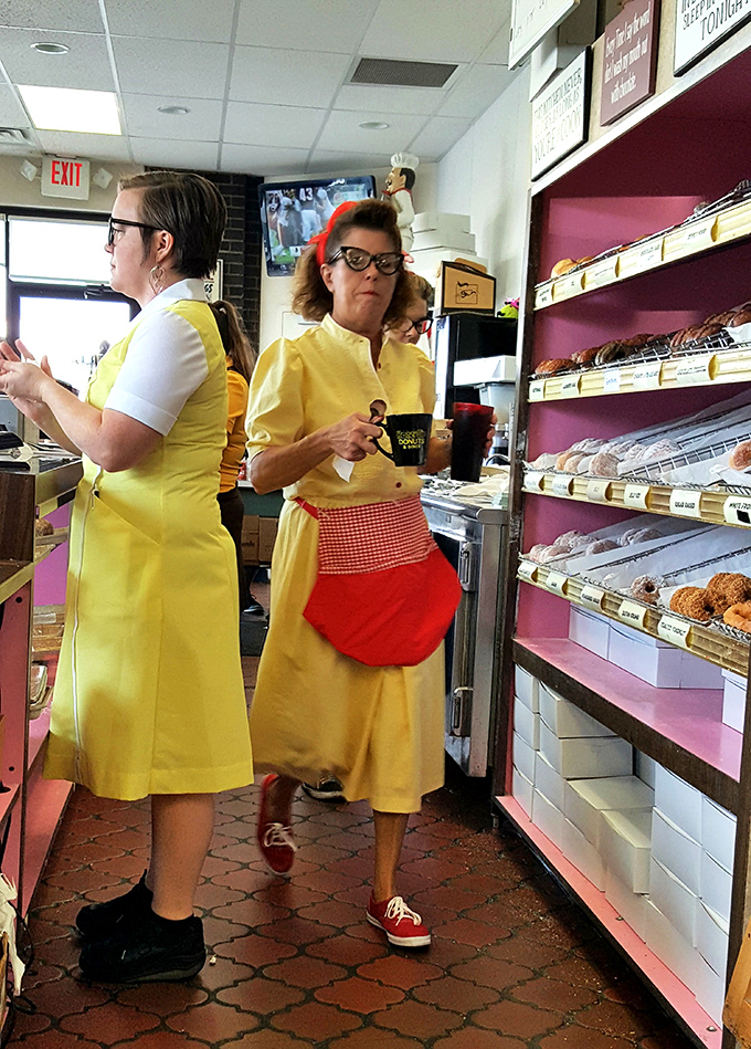 The yellow-uniformed donut artisans, guardians of morning happiness, working their magic behind the counter like breakfast scientists.