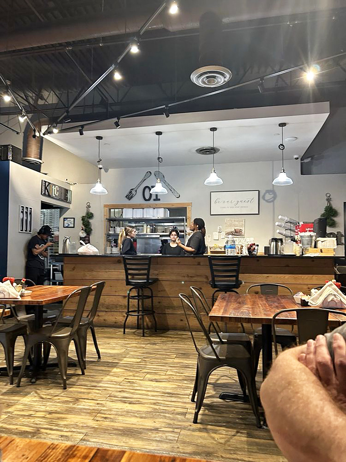 Behind the wooden counter, culinary magic happens. The open kitchen design means you can watch your breakfast dreams become delicious reality.