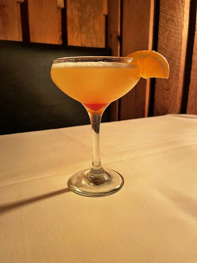 A sunset-hued cocktail that promises to take the edge off your day, garnished with an orange slice that's not just there for decoration.