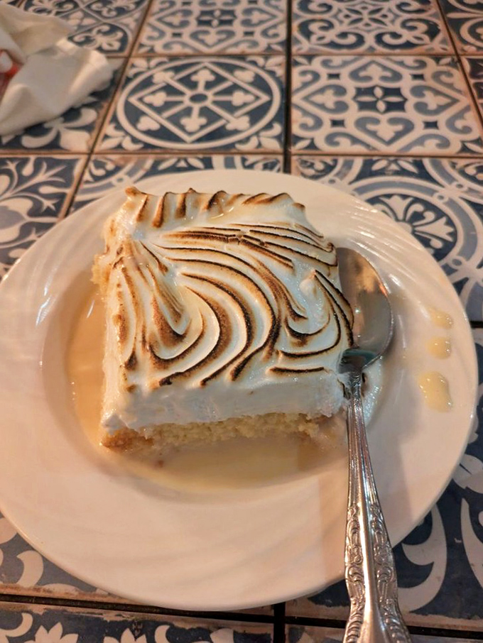 Tres leches cake with torched meringue peaks—a sweet cloud floating on milk-soaked sponge that makes grown adults fight for the last bite.