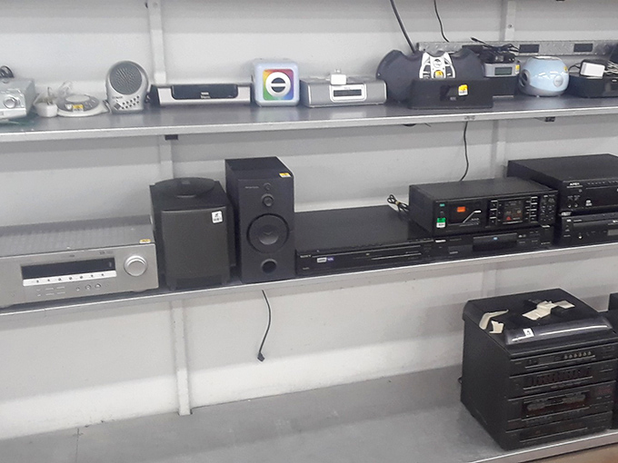 An antique radio sits beneath modern entertainment systems&mdash;a multi-generational family reunion of technology spanning decades, all priced to move.