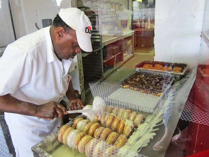 Craftsmanship in action. Each donut receives the focused attention of hands that have performed this delicious choreography thousands of times.