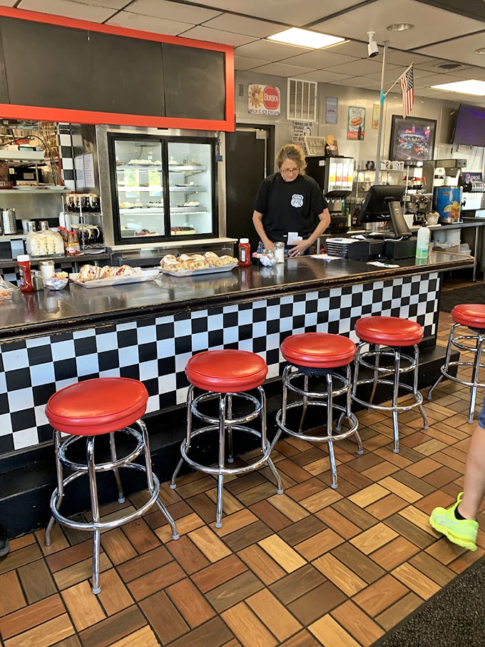 The classic checkered counter with fire-engine red stools &ndash; where solo diners find community and regulars have their names invisibly engraved.
