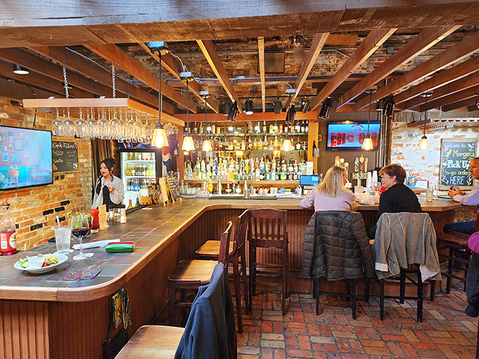 The bar area combines brick, wood, and bottles in a trinity of tavern perfection where stories flow as freely as the drinks.