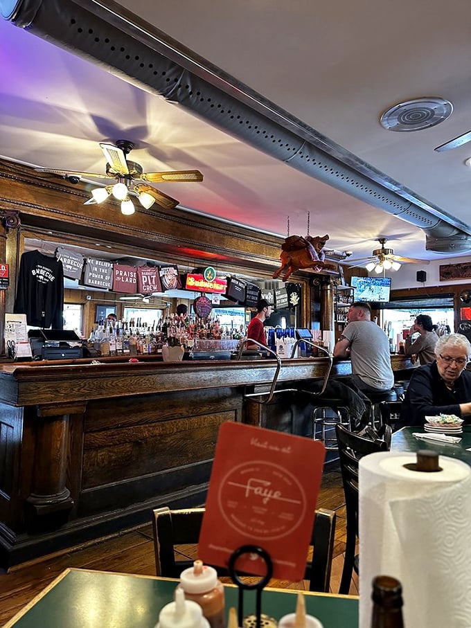 The warm glow of neon signs illuminates a bar where strangers become friends, united by the universal brotherhood of barbecue appreciation.