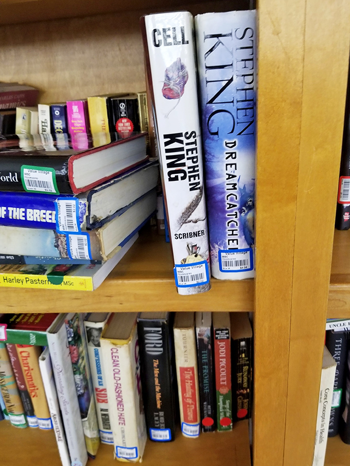 A bookshelf features a collection of used books, with several hardcover novels by Stephen King prominently displayed.