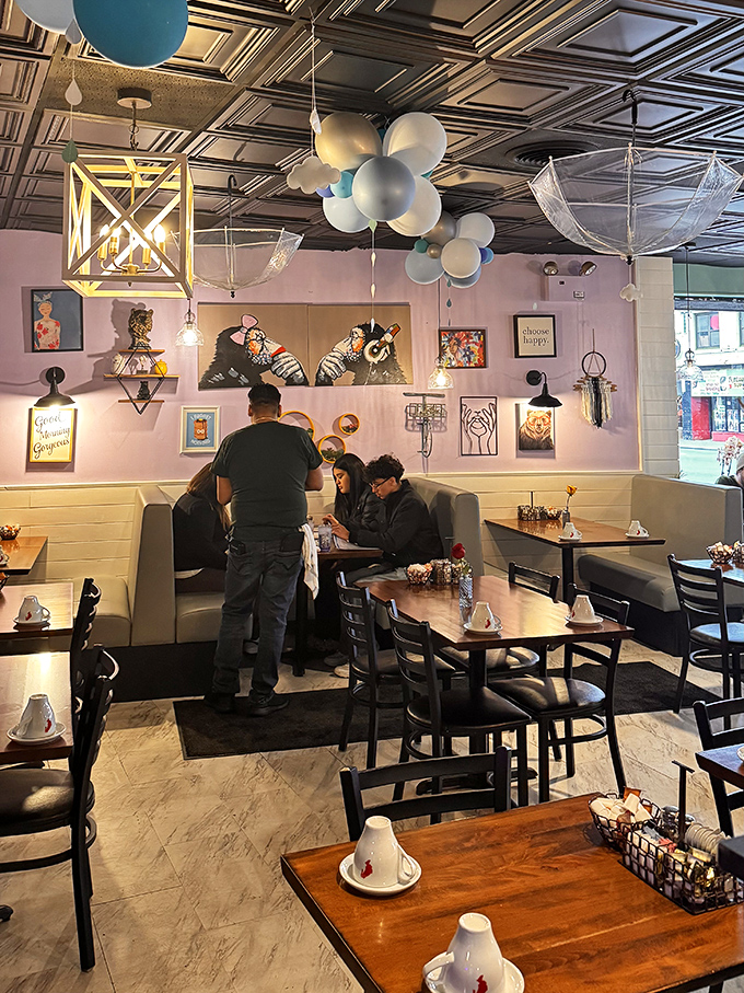 The pink accent wall and playful art create a dining nook that's equal parts Instagram backdrop and comfort zone.