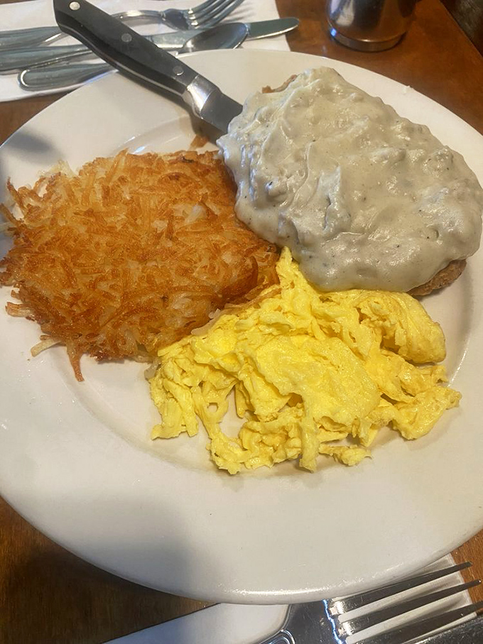 The holy trinity of breakfast: golden hash browns, fluffy scrambled eggs, and chicken fried steak with gravy. A morning masterpiece.