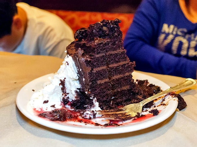 A chocolate cake so tall and imposing it needs its own zip code. The fork is there for optimists who think they can finish it.